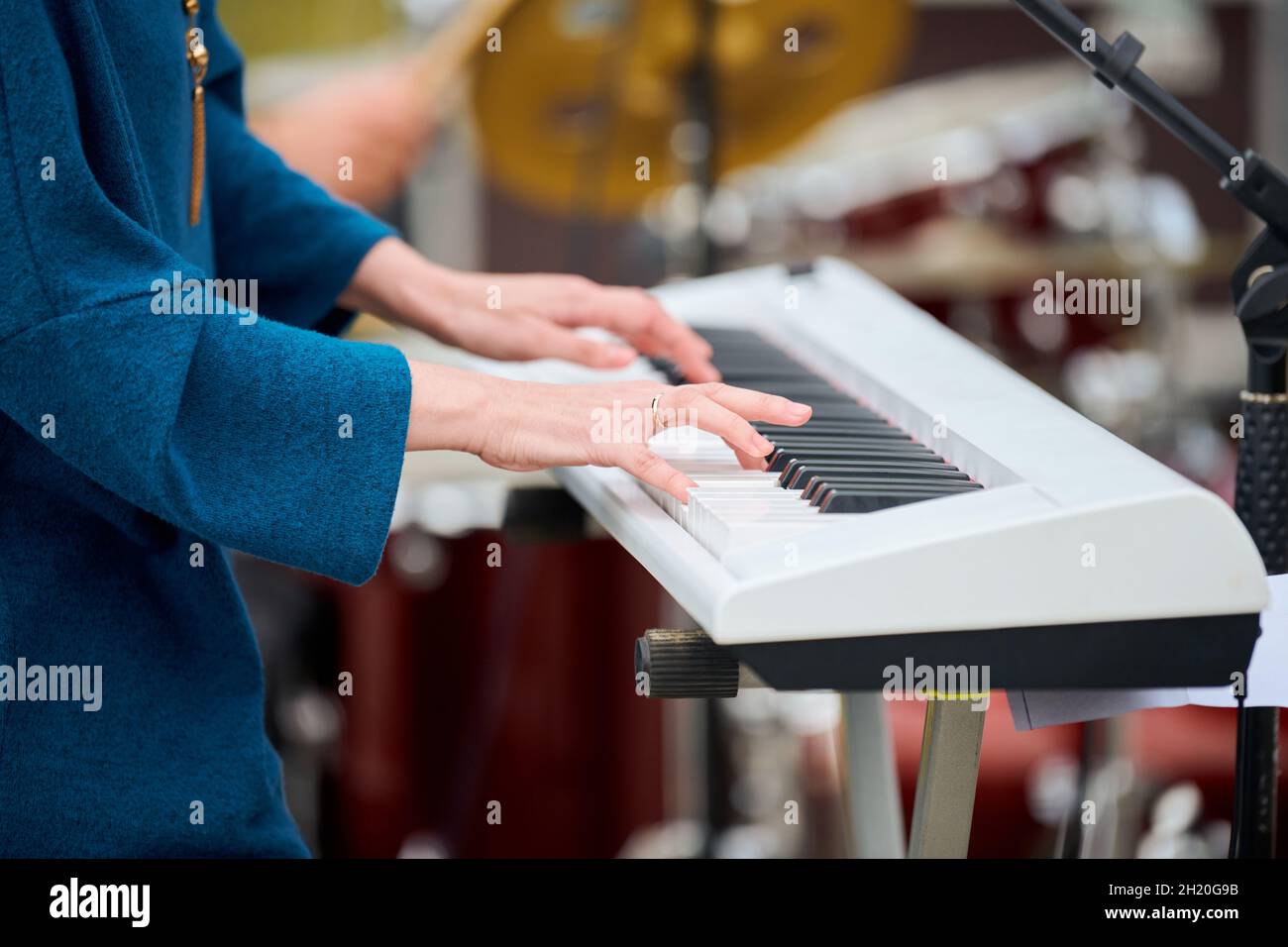 Musician woman playing on white synthesizer keyboard piano keys, focus ...