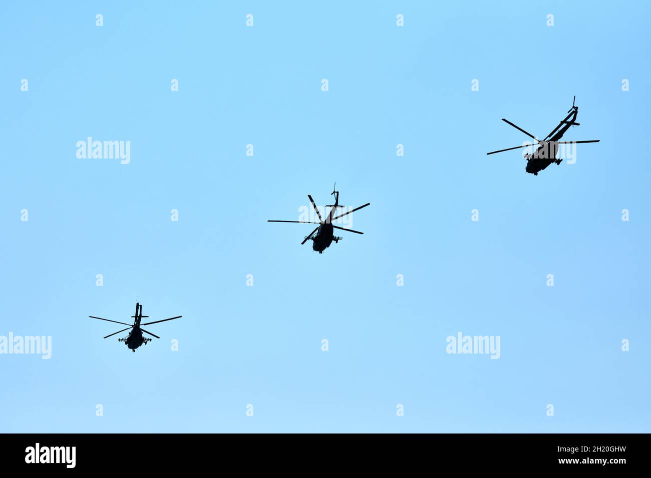 Three military helicopters flying in bright blue sky while performing ...