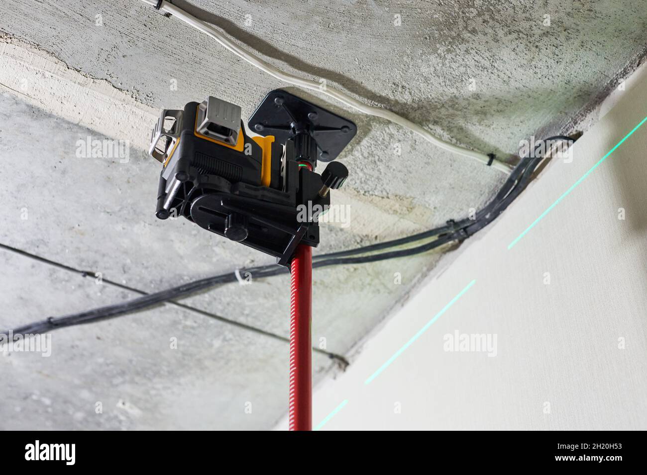 Laser level measuring tool with visible green laser beam on wall at ...