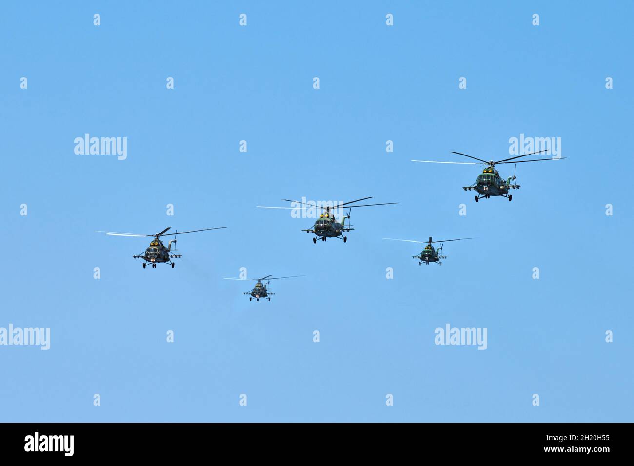 Military helicopters flying in bright blue sky performing demonstration ...
