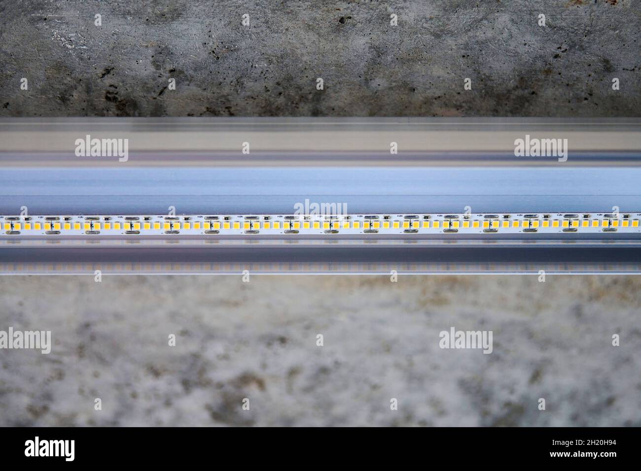 LED strip with aluminum profile on rough wall. Concrete ceiling with ...