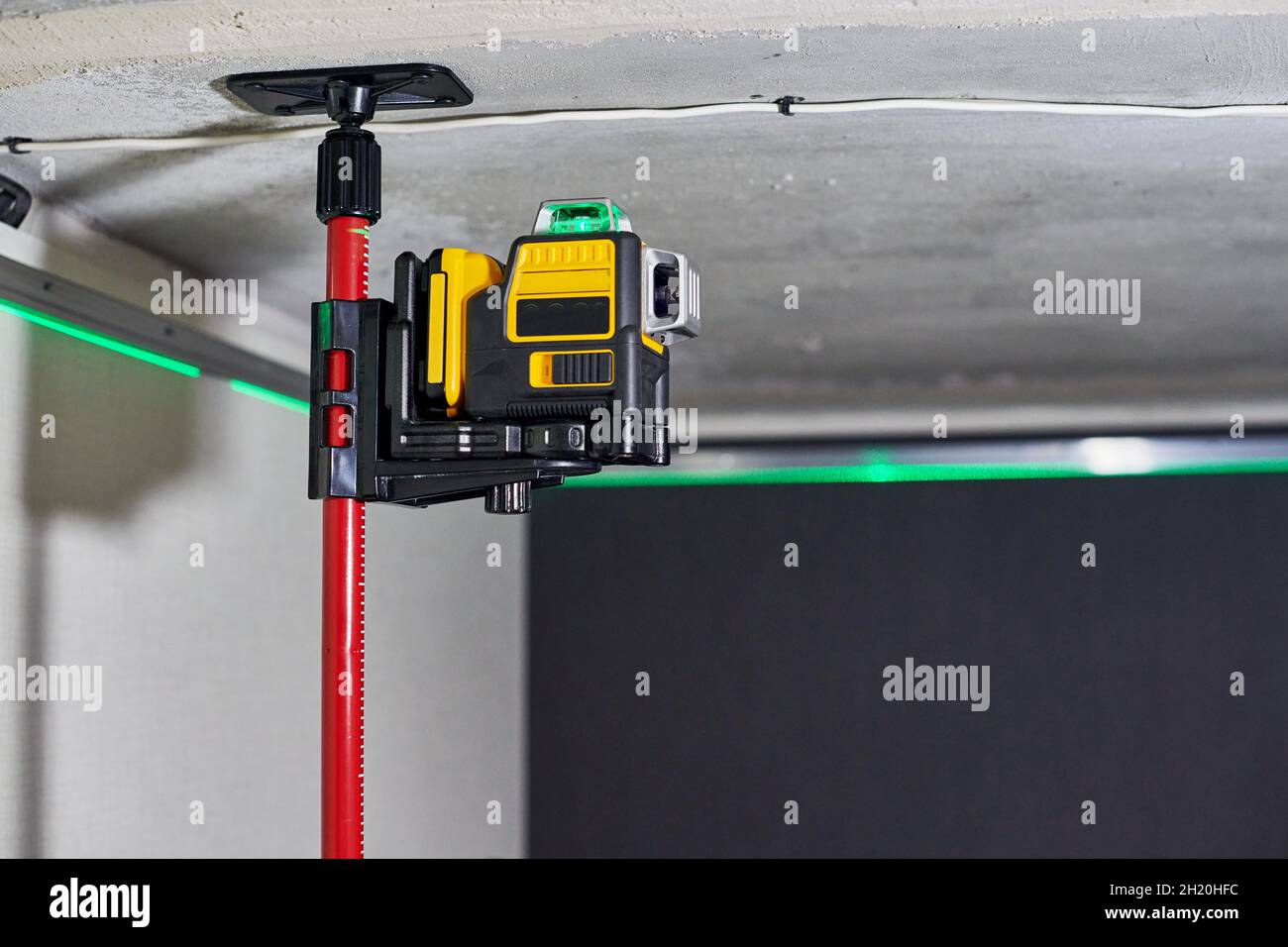 Laser level measuring tool with visible green laser beam on wall at ...