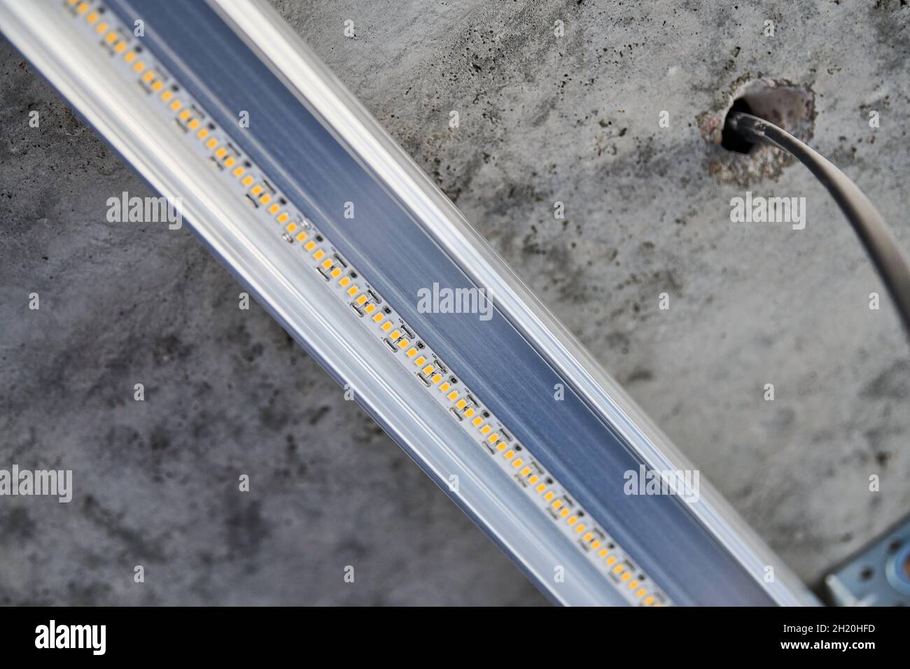 LED strip with aluminum profile on rough wall. Concrete ceiling with ...