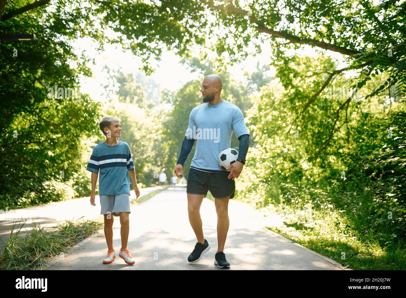 Father and son, football players on walking path Stock Photo - Alamy