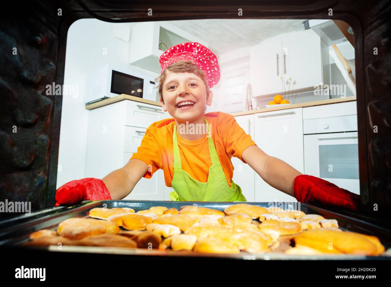 Happy laughing boy take baked cookies from oven Stock Photo - Alamy