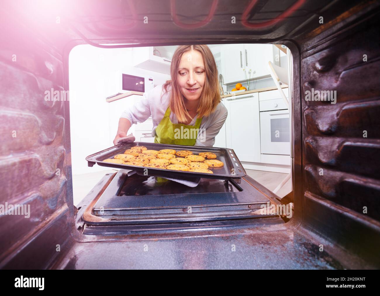 Woman take tray with cookies from oven inside view Stock Photo - Alamy