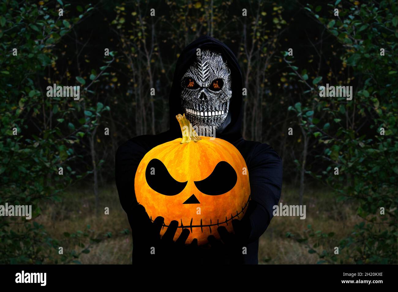 Grim reaper holding halloween pumpkin head. Man in death mask with fire ...