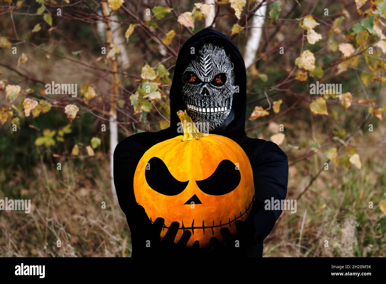 Grim reaper holding halloween pumpkin head. Man in death mask with fire ...