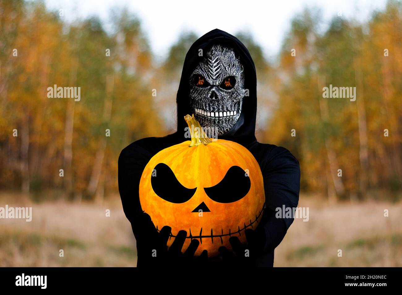 Grim reaper holding halloween pumpkin head. Man in death mask with fire ...