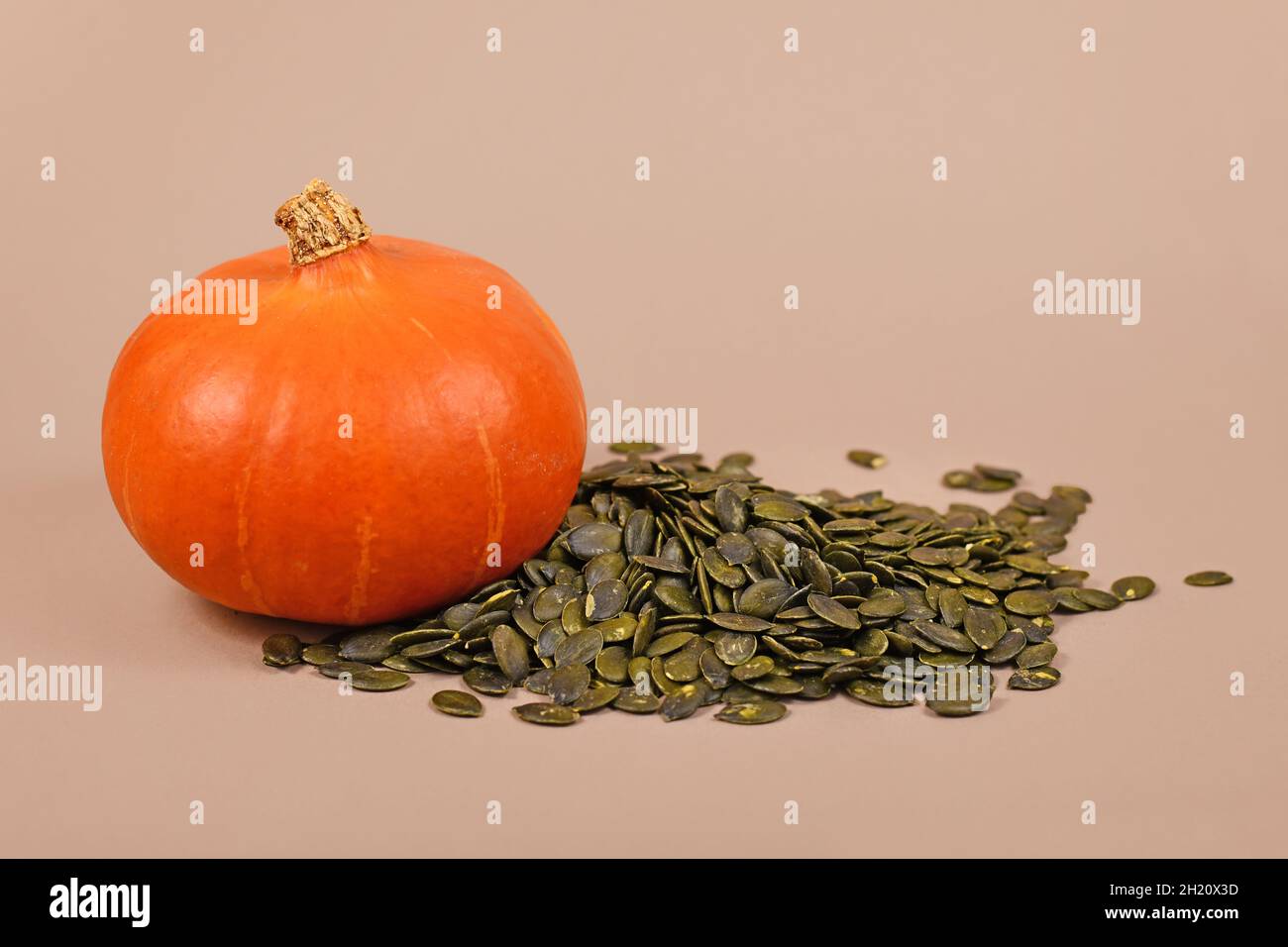 Green pumpkin seeds next to whole 'Red Kuri Hokkaido' squash Stock ...