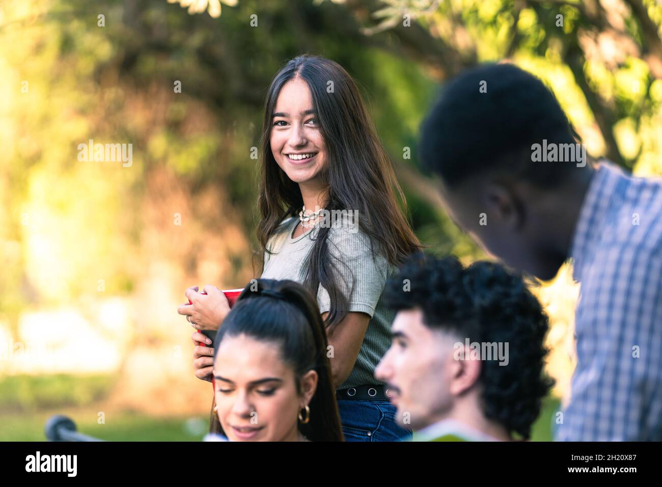 Caucasian woman sitting on a bench next to a multiethnic group of ...