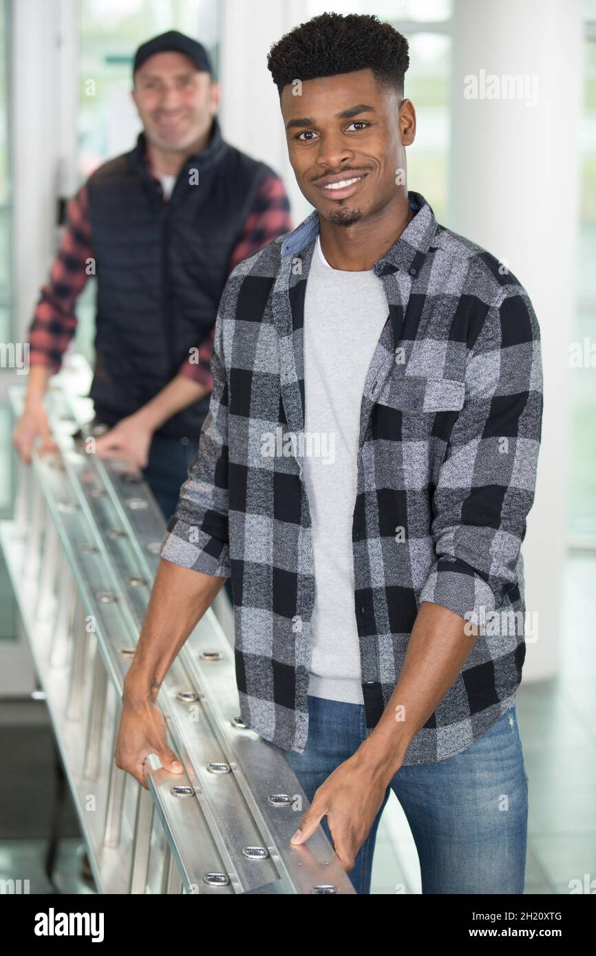 cheerful men carrying a ladder Stock Photo - Alamy