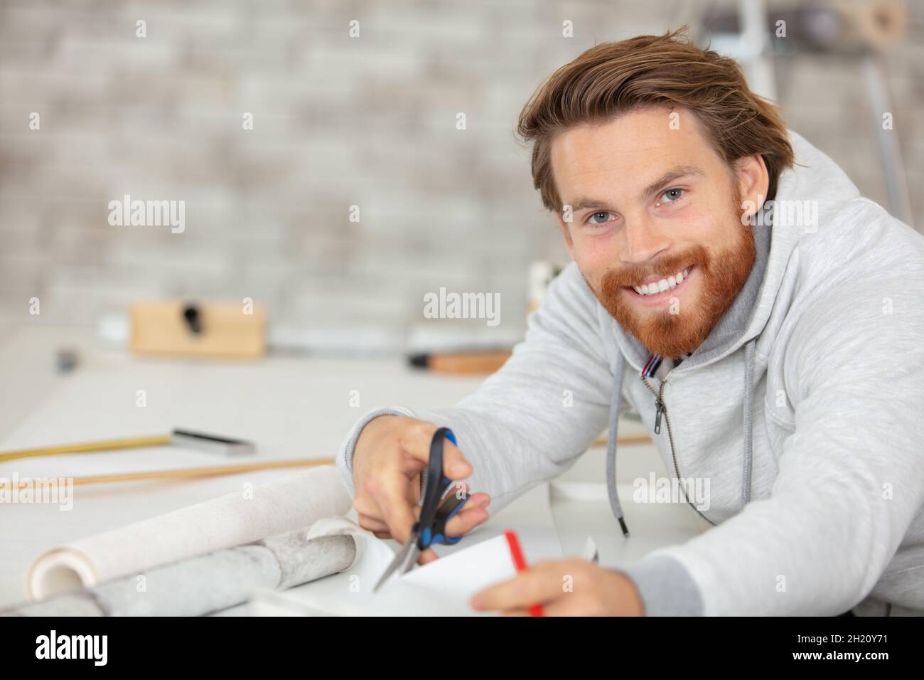 man cutting wallpaper with scissors Stock Photo - Alamy