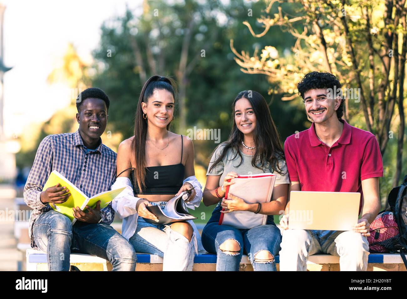 Group of friends facing the camera while sitting on a bench with ...