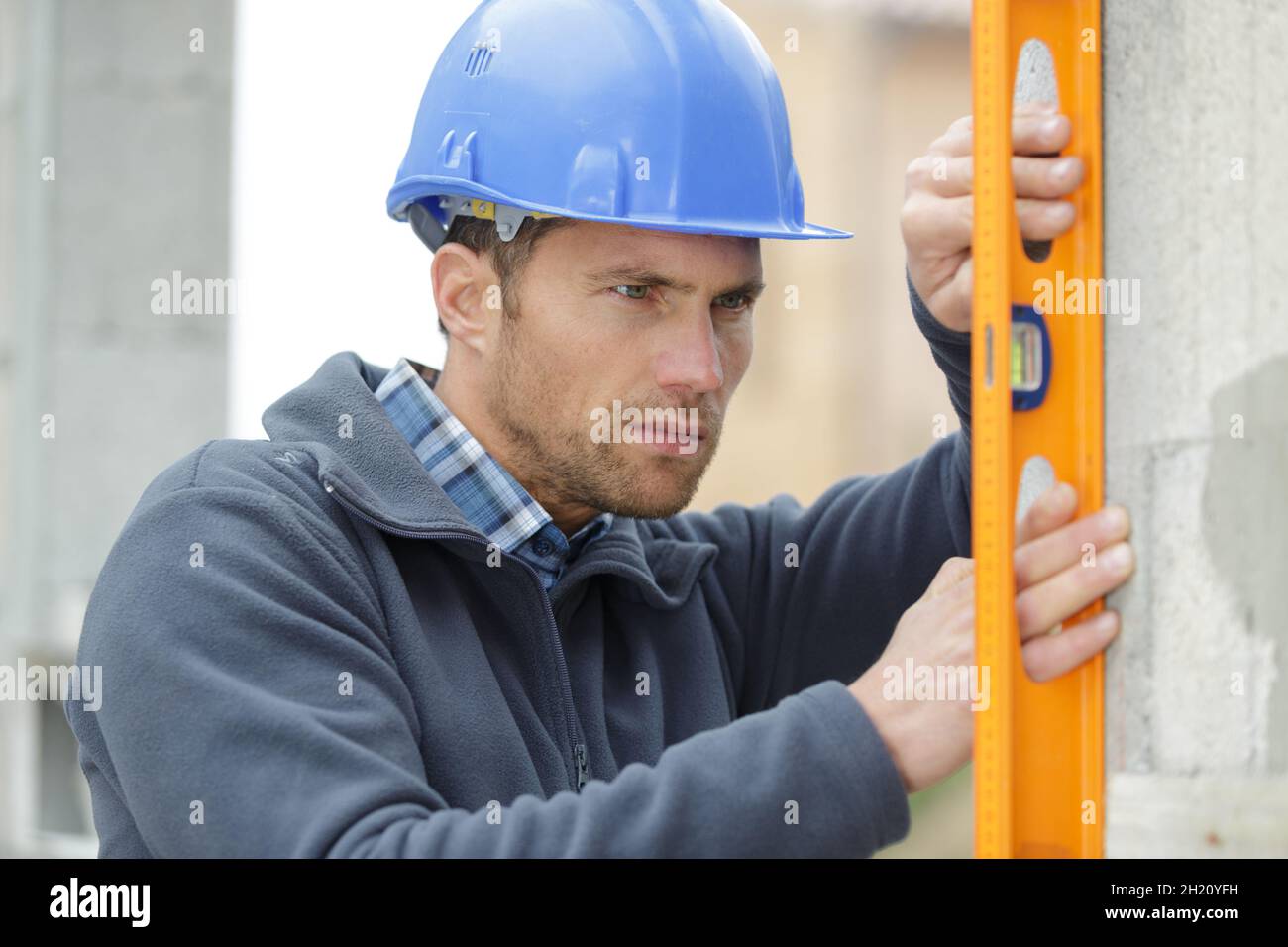 builder on site checking outdoor wall with spirit level Stock Photo - Alamy
