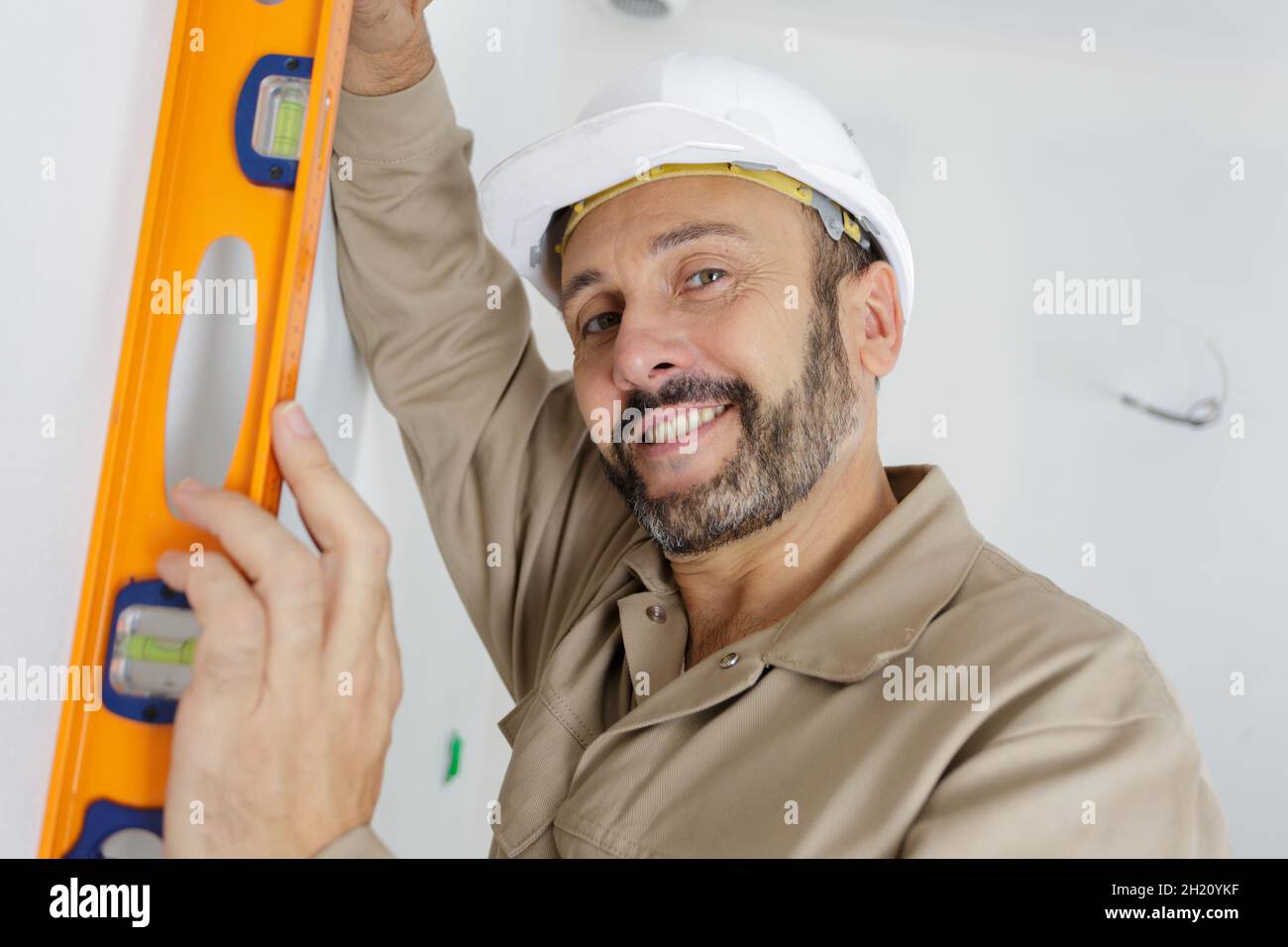 man using spirit level on wall Stock Photo - Alamy