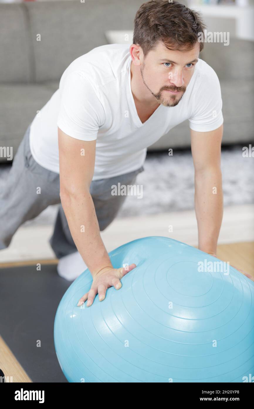 handsome man in sportswear holding plank with fitball Stock Photo - Alamy