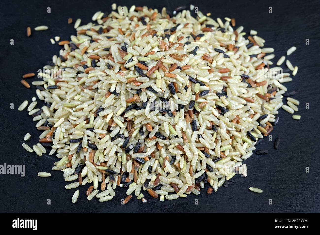 Heap of rice mixed from different varieties on a black board. a mixture ...