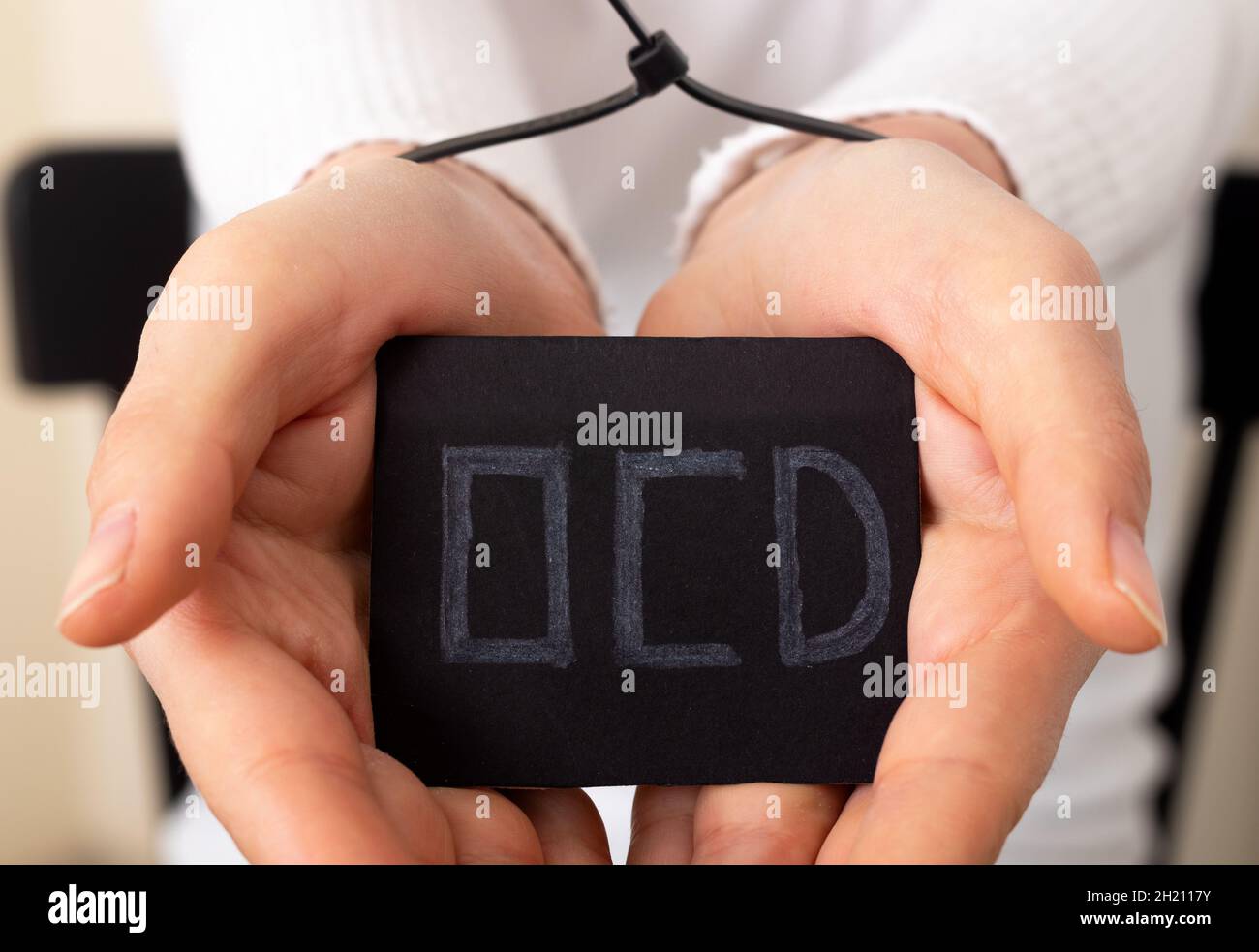Woman holding black card written OCD and hands are teid with plastic ...