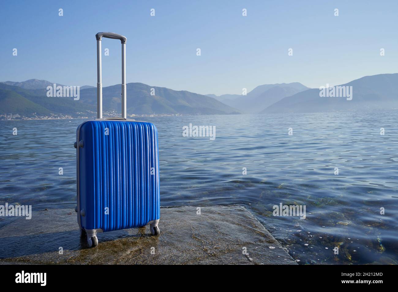 Blue suitcase against the background of the sea and mountains Stock ...
