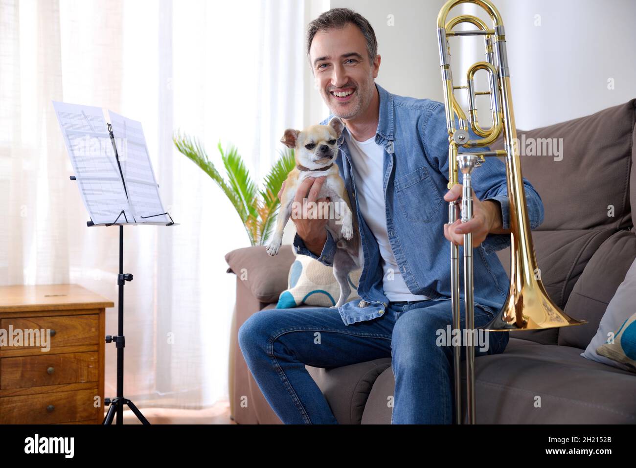 Man with his dog while practicing the trombone in his leisure time in ...