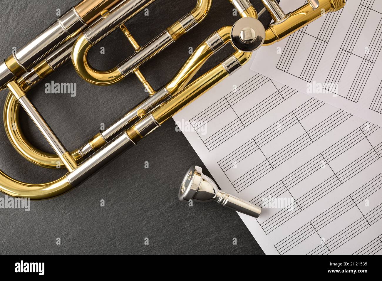 Trombone pipe and mechanism detail with empty pentagram sheets on slate ...
