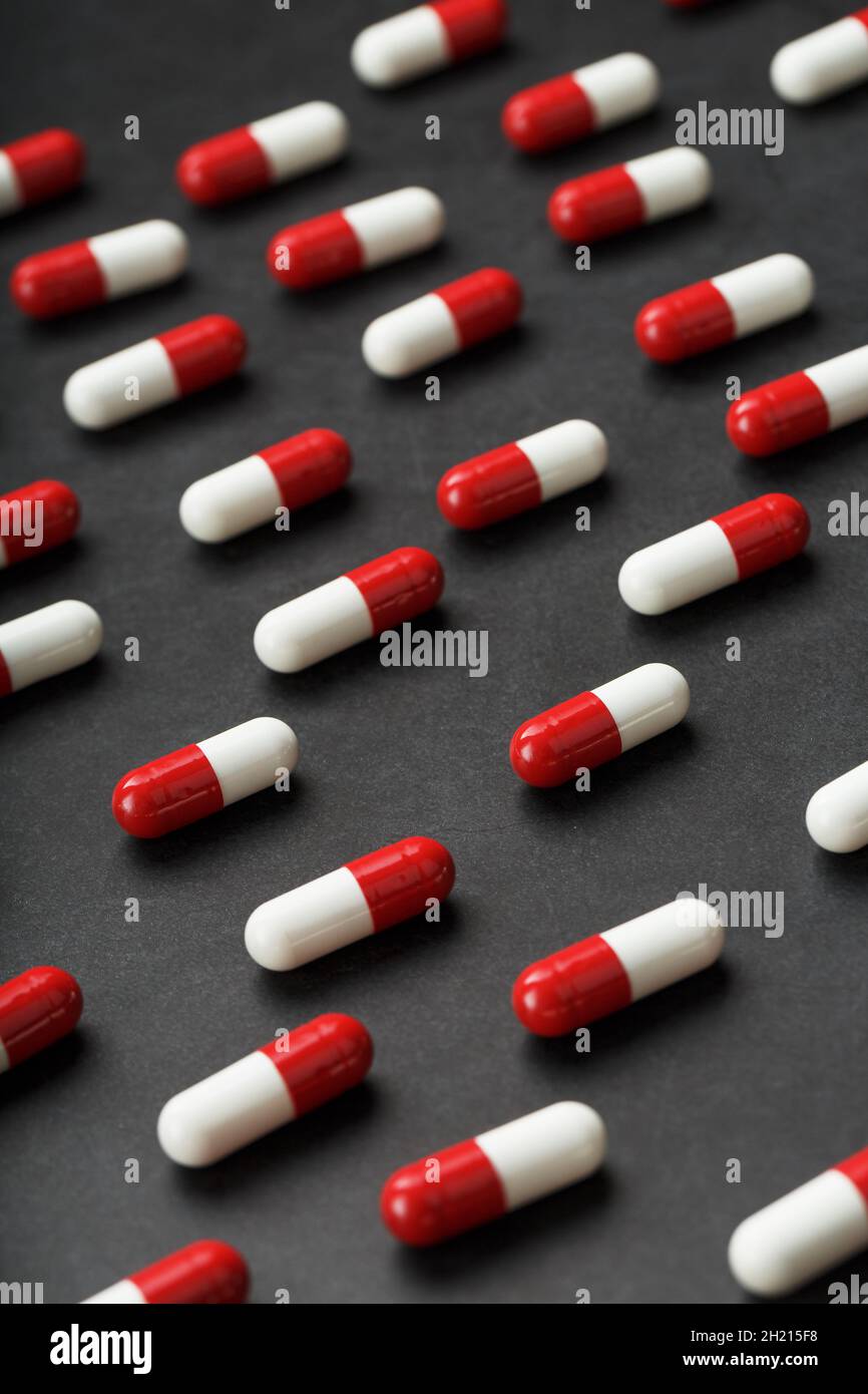A pattern of red and white pill capsules on a black background ...