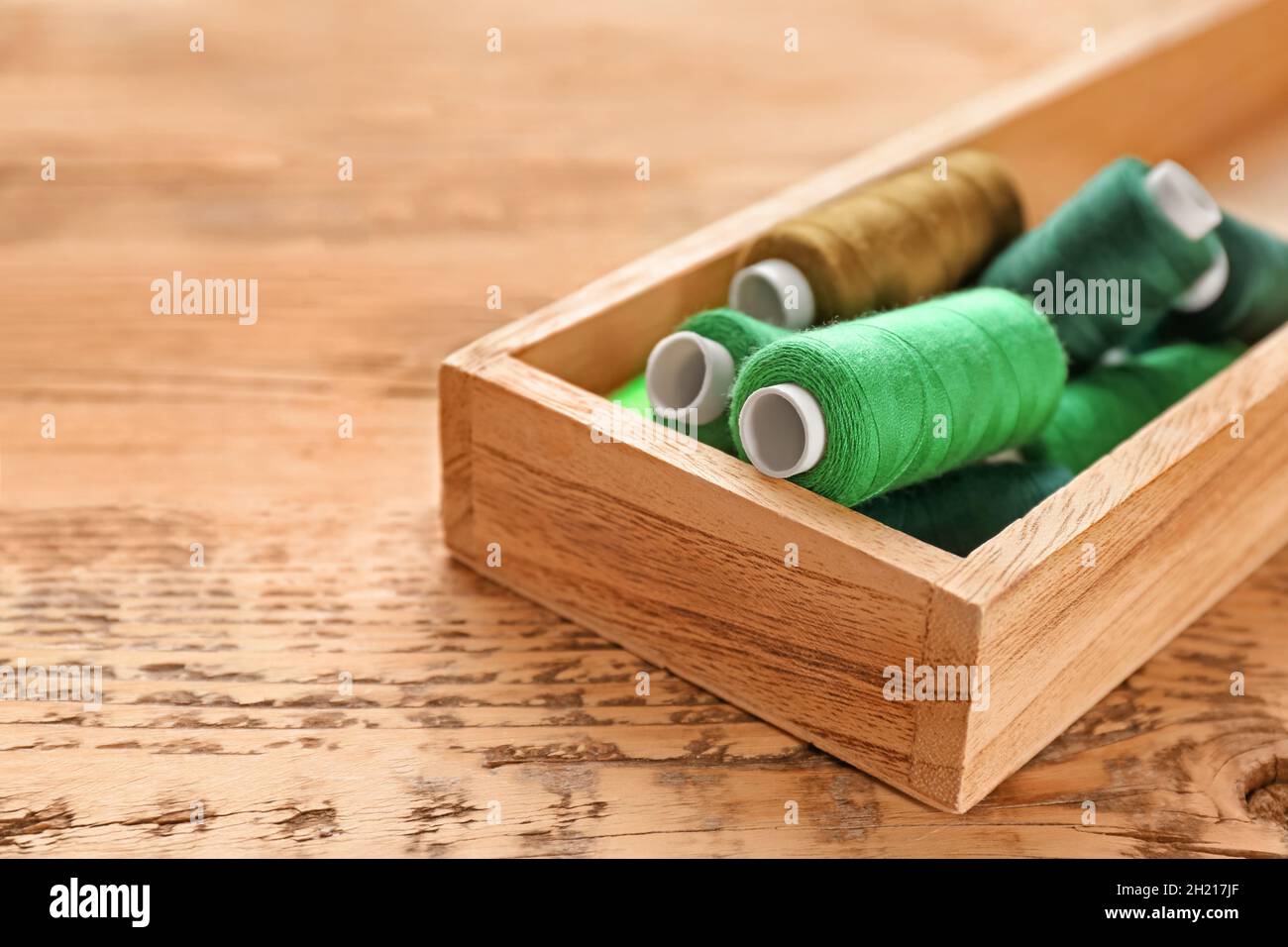 Container with set of color sewing threads on wooden background Stock ...