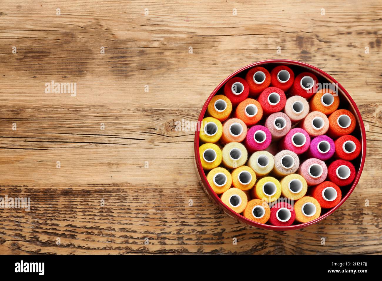 Container with set of color sewing threads on wooden background Stock ...
