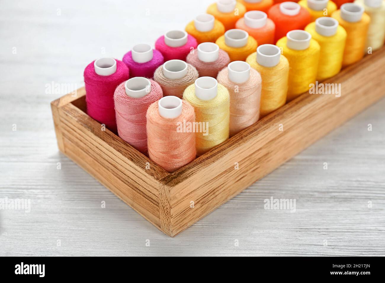 Container with set of color sewing threads on wooden background Stock ...