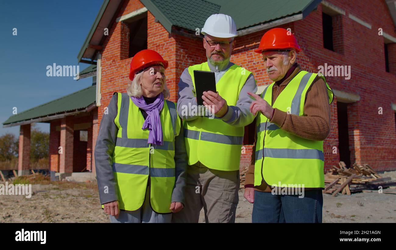 Real estate agent manager architect showing modern house to senior ...