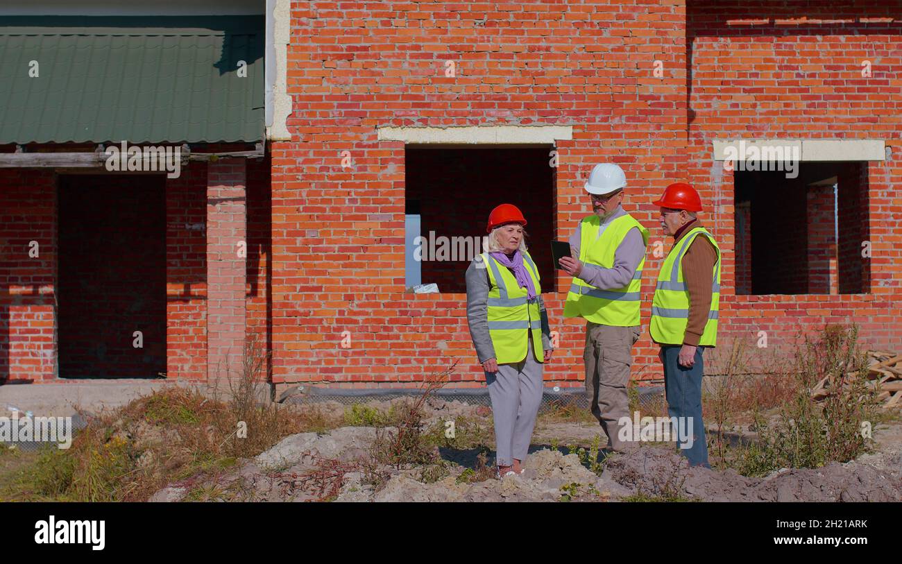 Real estate agent manager architect showing modern house to senior ...