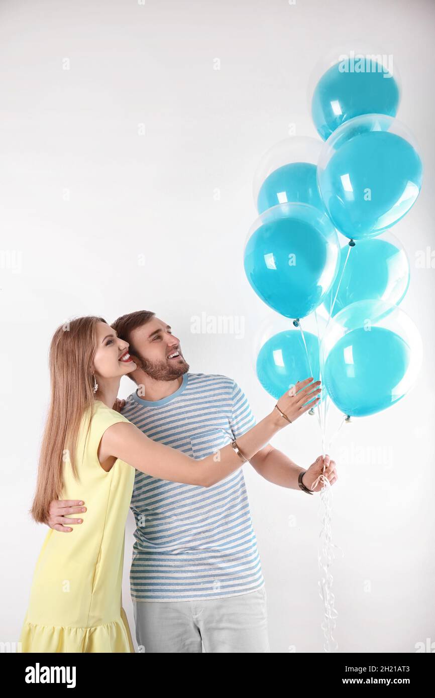 Young couple with air balloons on white background Stock Photo - Alamy