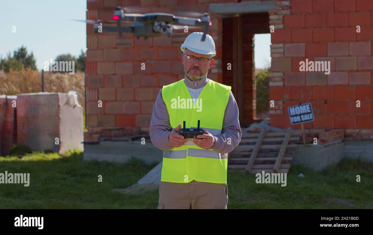 Drone operator holding remote controller controls an aircraft in front ...