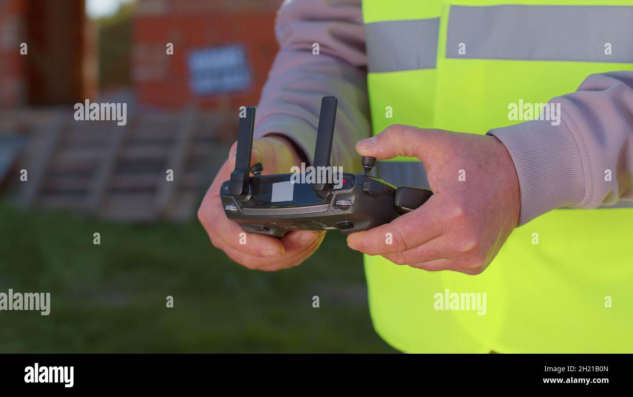 Drone operator holding remote controller controls an aircraft in front ...