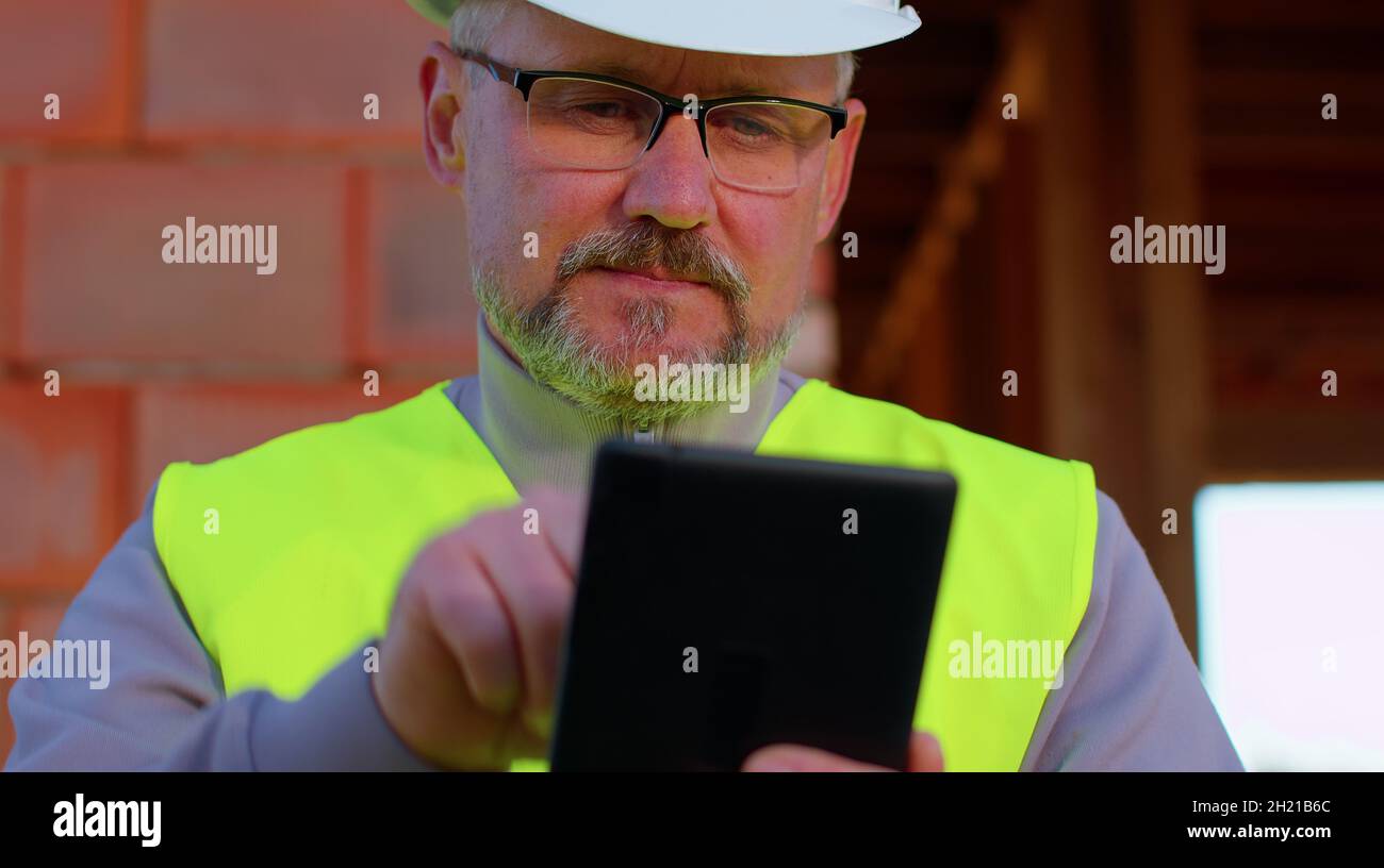 Architect Man With Digital Tablet Computer At Construction Site Analyzing Blueprints Building