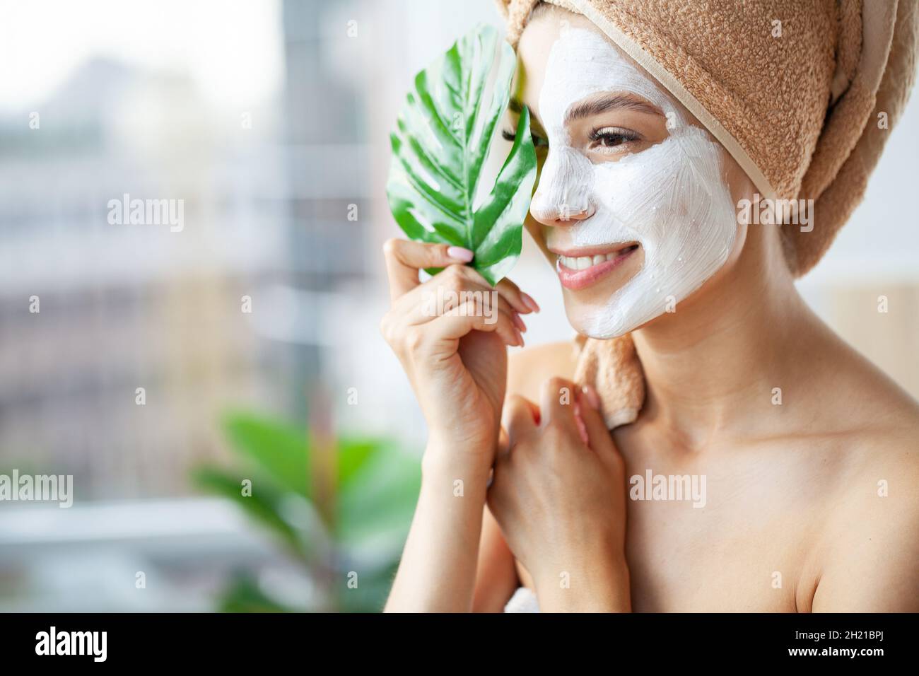 Beautiful young woman applying facial mask on her face Stock Photo - Alamy