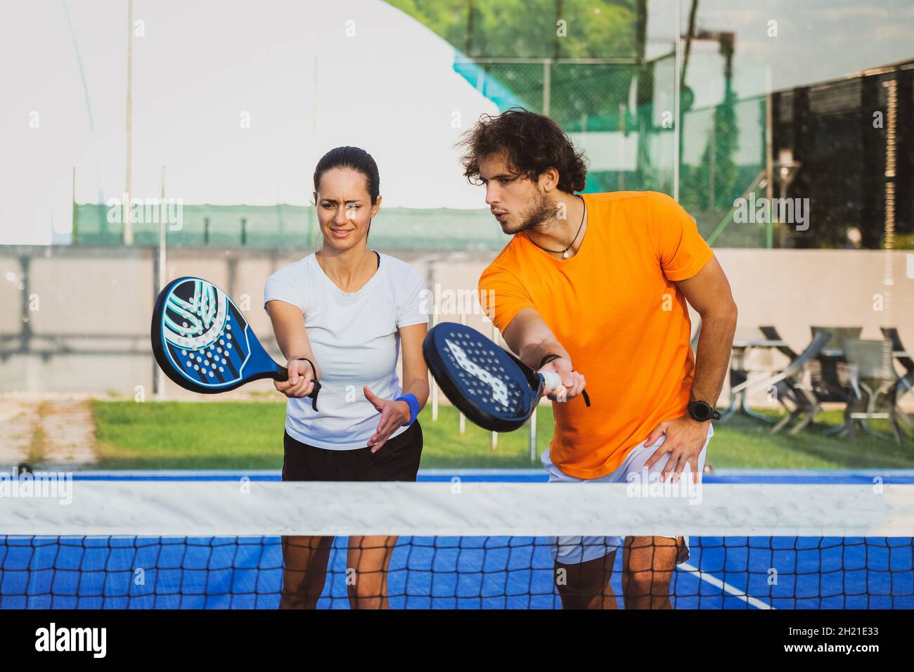 Young teacher is monitoring teaching padel lesson to his student ...