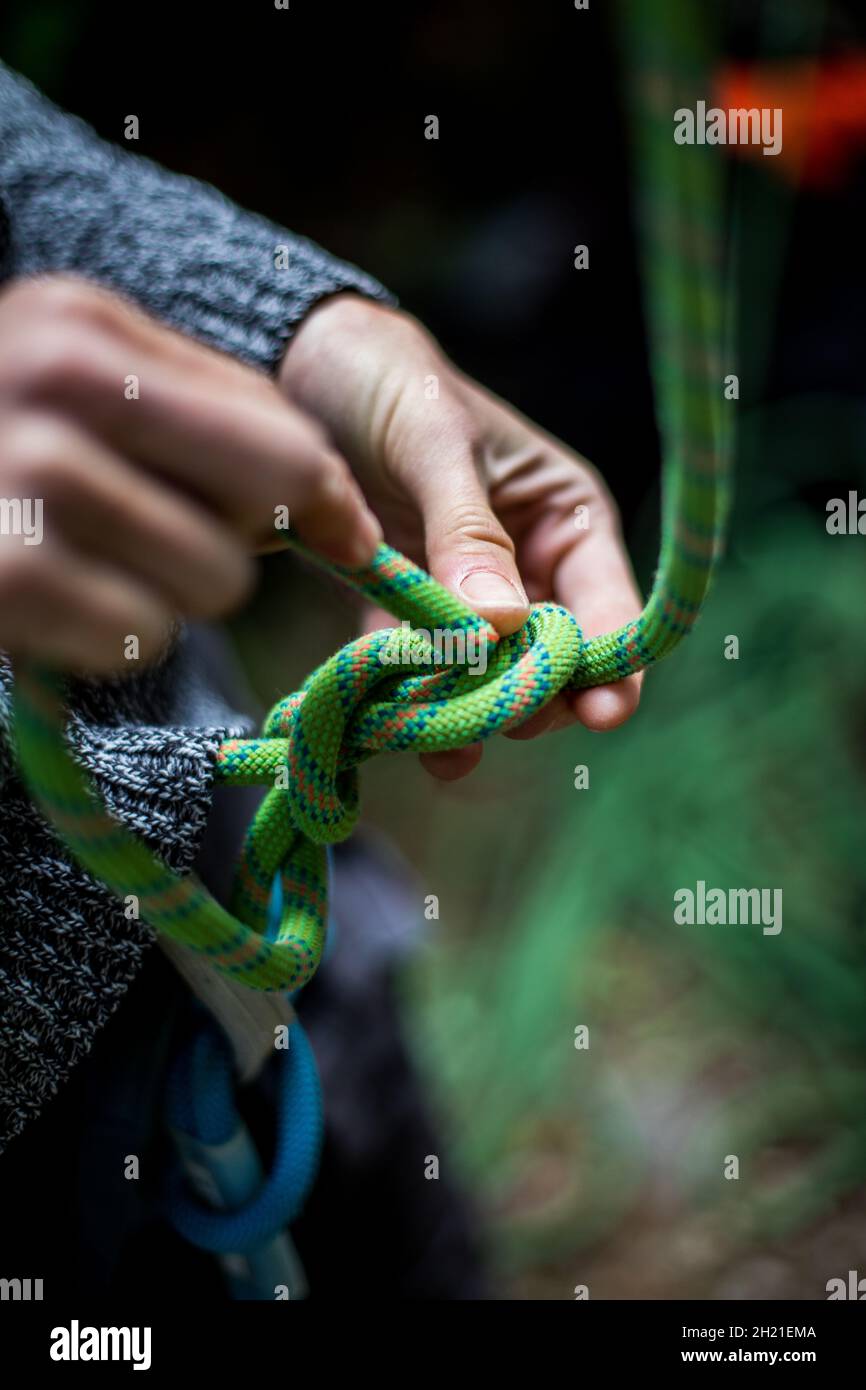 Detail with a climber's hands tying a figure eight know to the harness ...