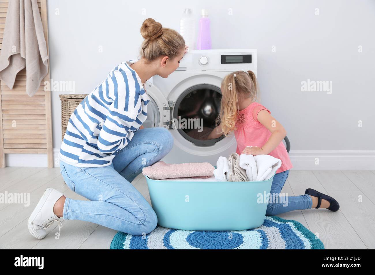 Little girl helping her mother to do laundry at home Stock Photo - Alamy