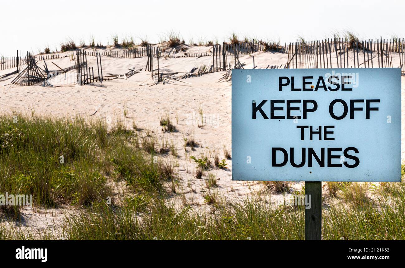 Keep off the dunes sign in front of sand dunes with broken fences off ...