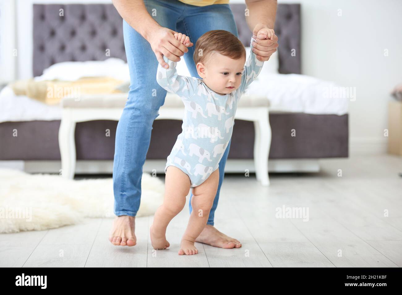 Baby taking first steps with father's help at home Stock Photo - Alamy