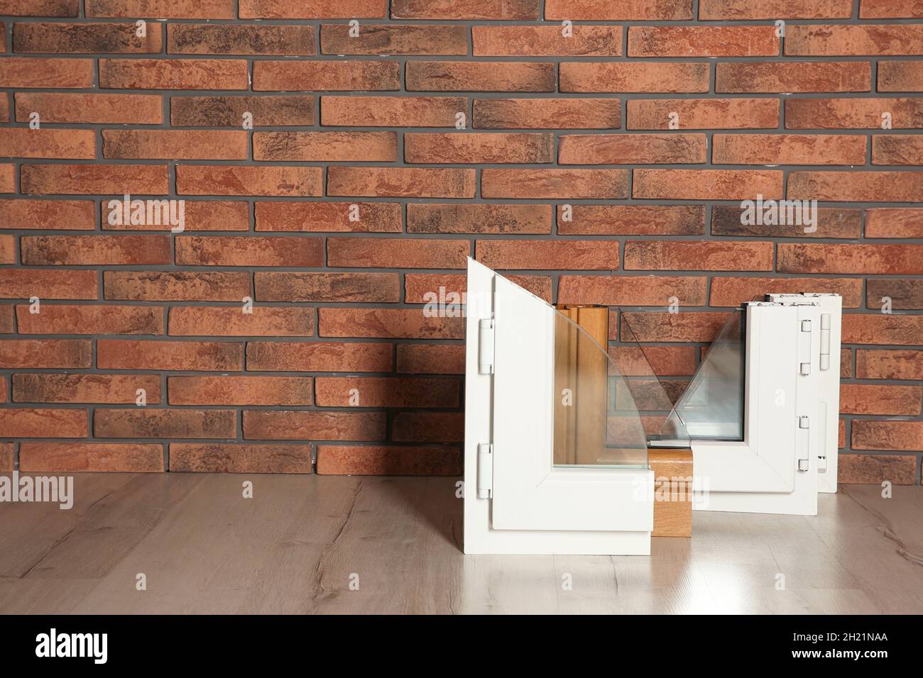 Samples of modern window profiles on floor against brick wall, space ...