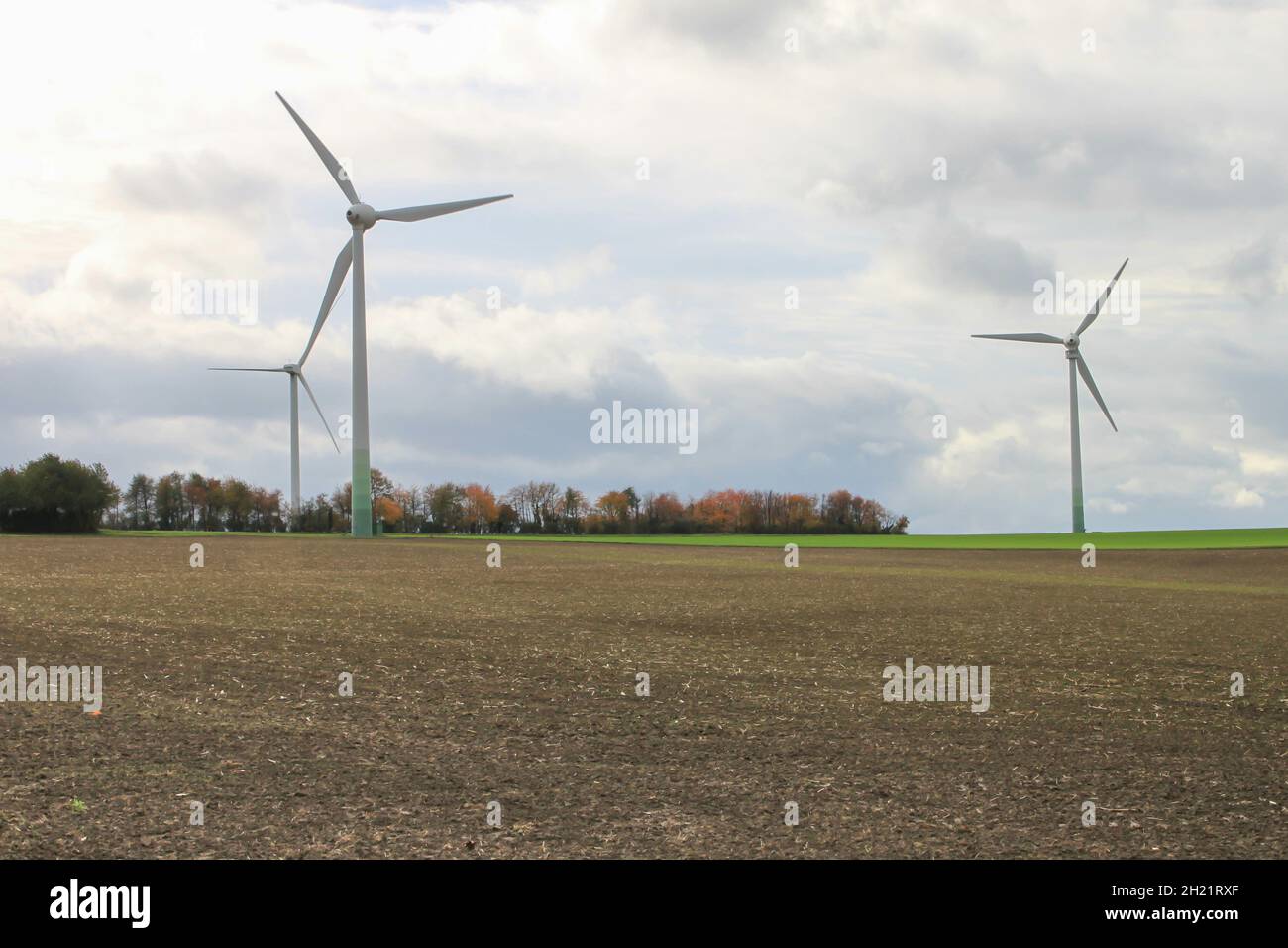 Beautiful shot of three white wind fans in a big field under a cloudy ...