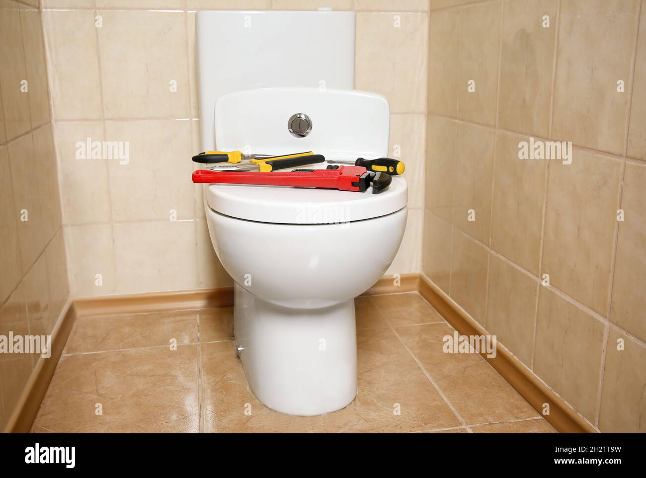 Different plumber's tools on toilet seat lid indoors Stock Photo - Alamy
