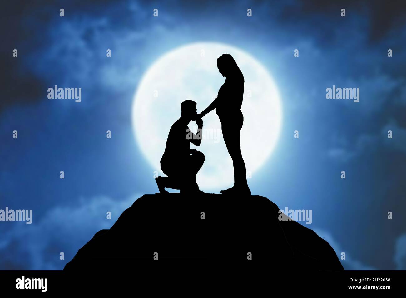 Silhouette of a romantic man on one knee kissing his partner's hand ...