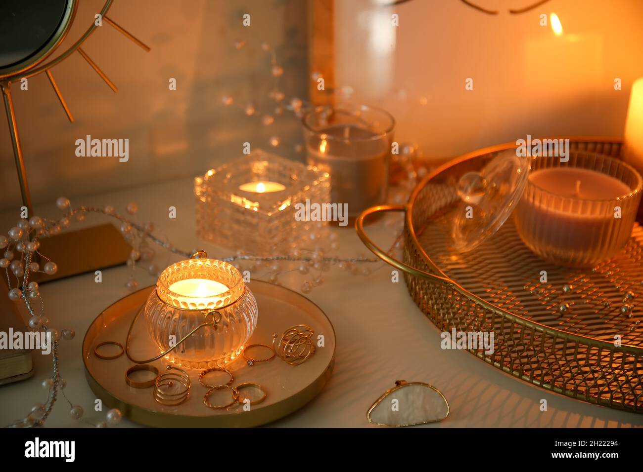 Glowing aroma candles with jewelry on table in dark room Stock Photo ...