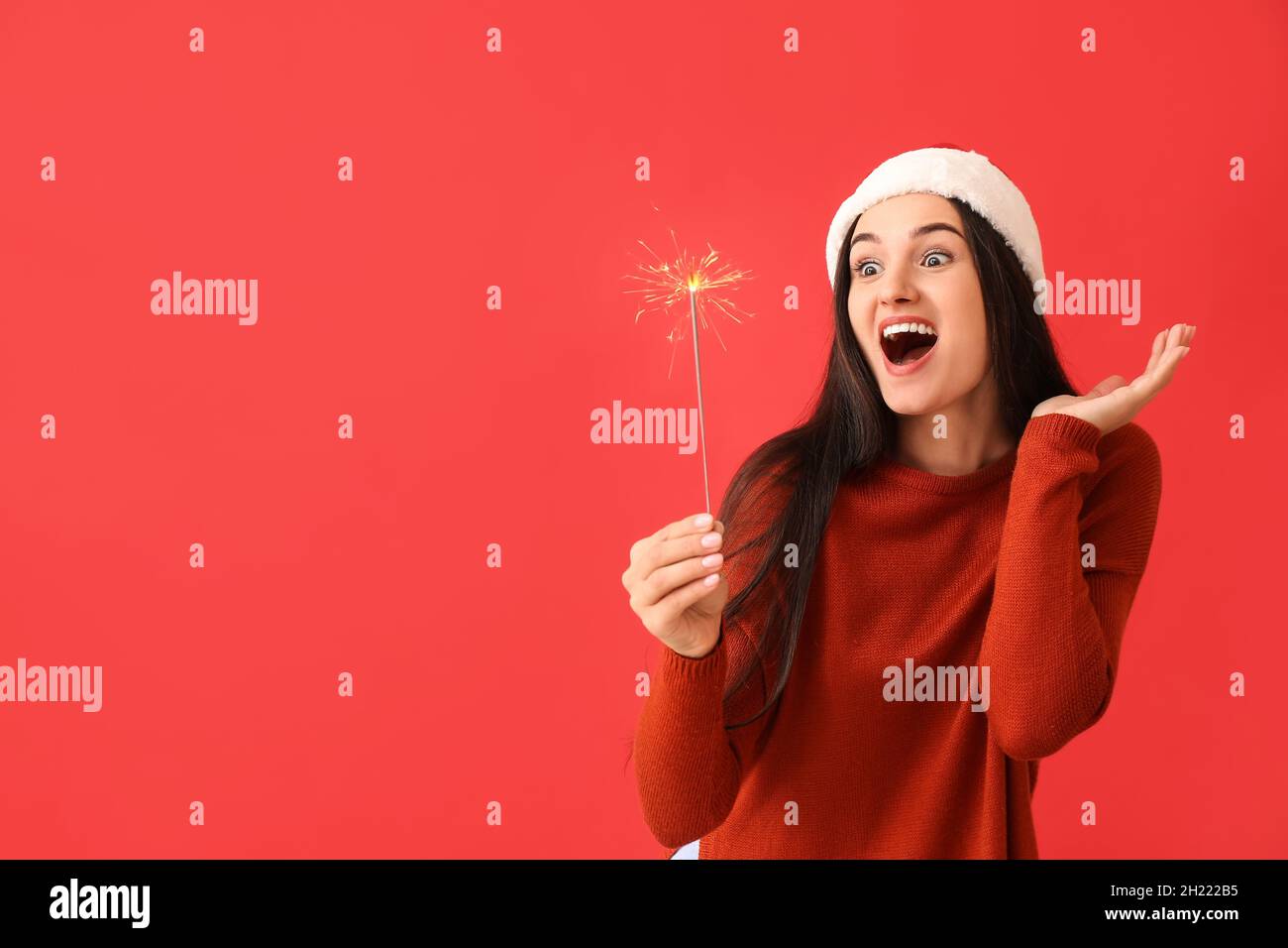 Excited woman with Christmas sparkler on red background Stock Photo - Alamy