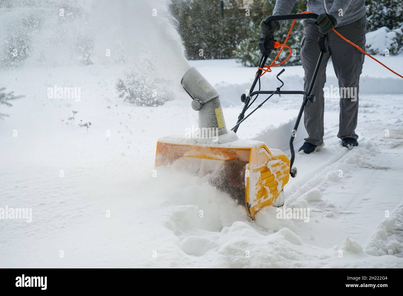 Man with machine removing snow in yard Stock Photo - Alamy