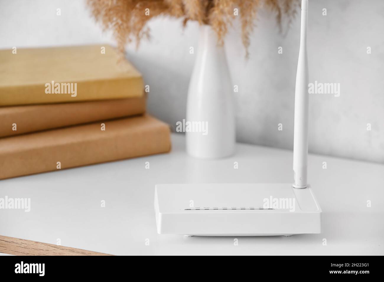 Modern wi-fi router on table near light wall Stock Photo - Alamy